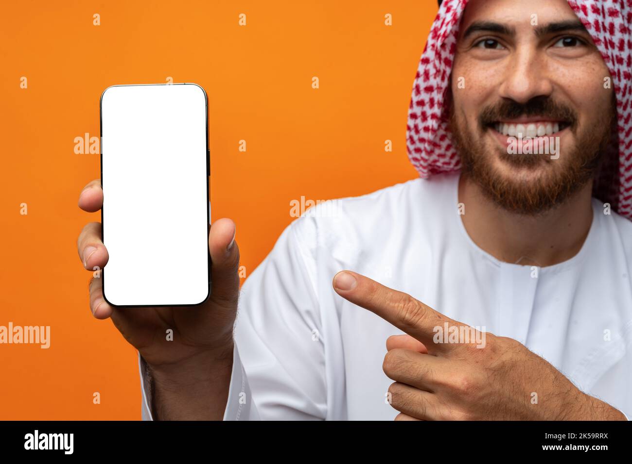 Young Arab muslim man in traditional clothes showing a mobile phone ...