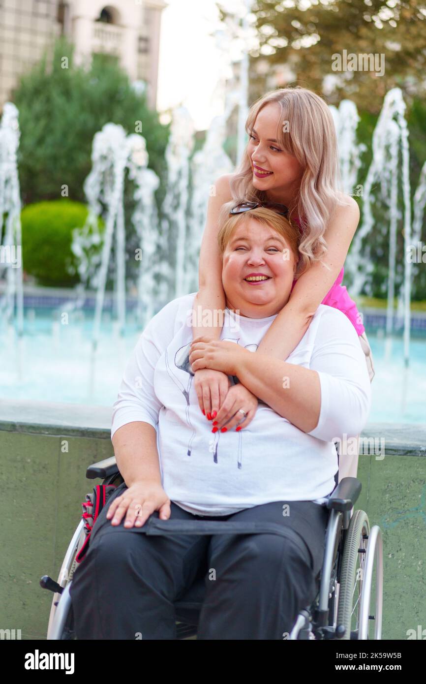 Young daughter taking care of her mother with disability sitting in ...