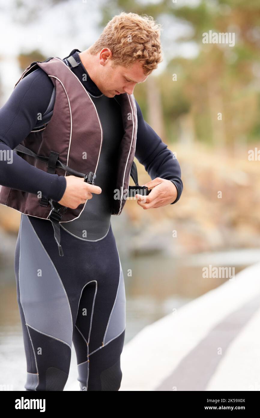 Clipping on his lifevest. Smiling young guy clipping on his life-vest ...