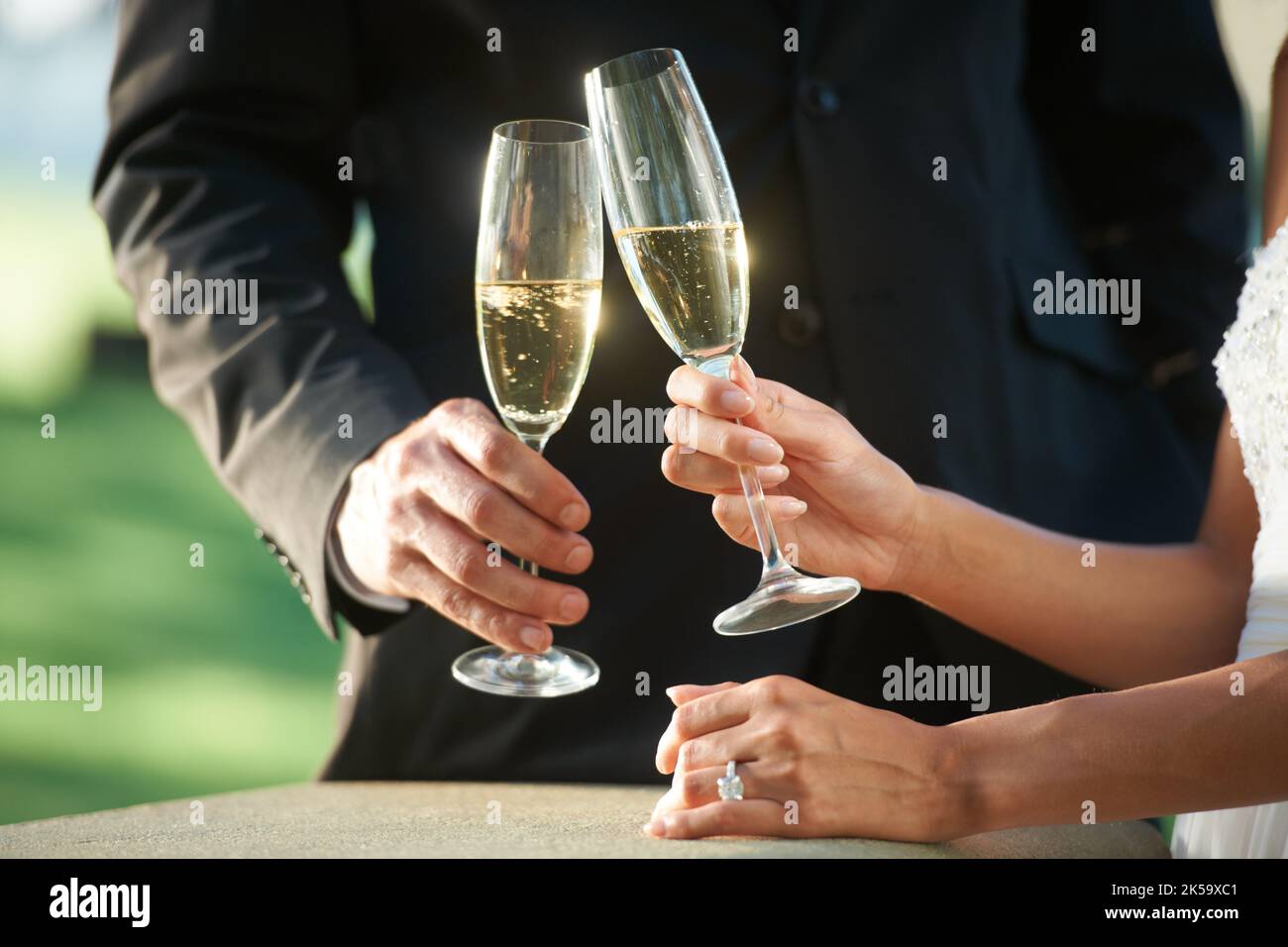Saying cheers. Cropped view of a young bride and groom standing ...