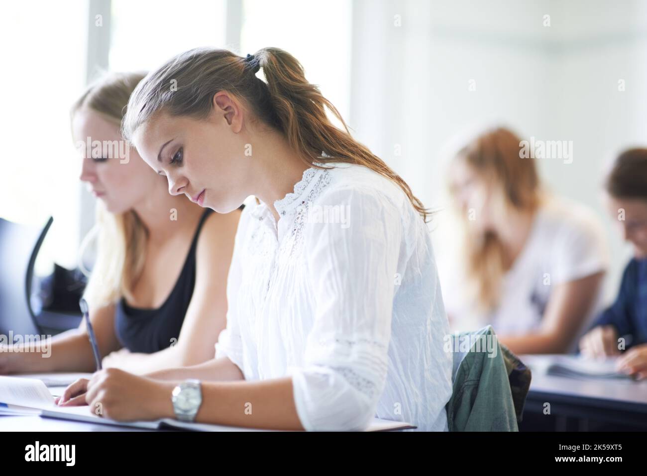 Working hard to finish first. A teenage girl sitting in a classroom ...
