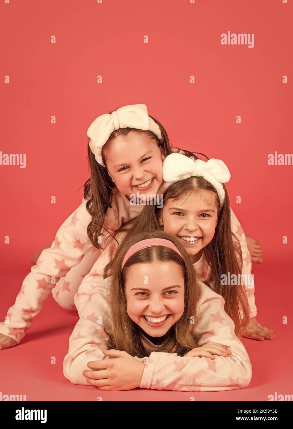 Pajama party is a real laugh. Happy sisters laughing lying close on ...