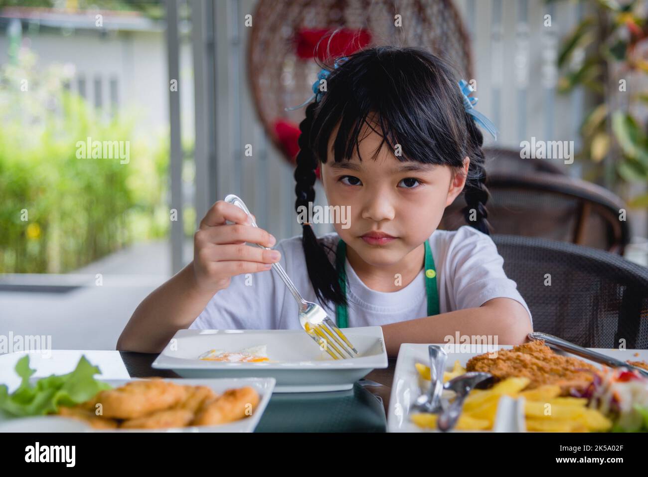 little girl asian eat fried egg on dish at table Stock Photo - Alamy