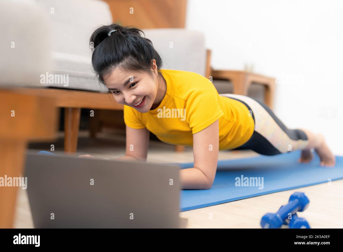 Happy asian woman working out at home and watching tutorial lesson on ...