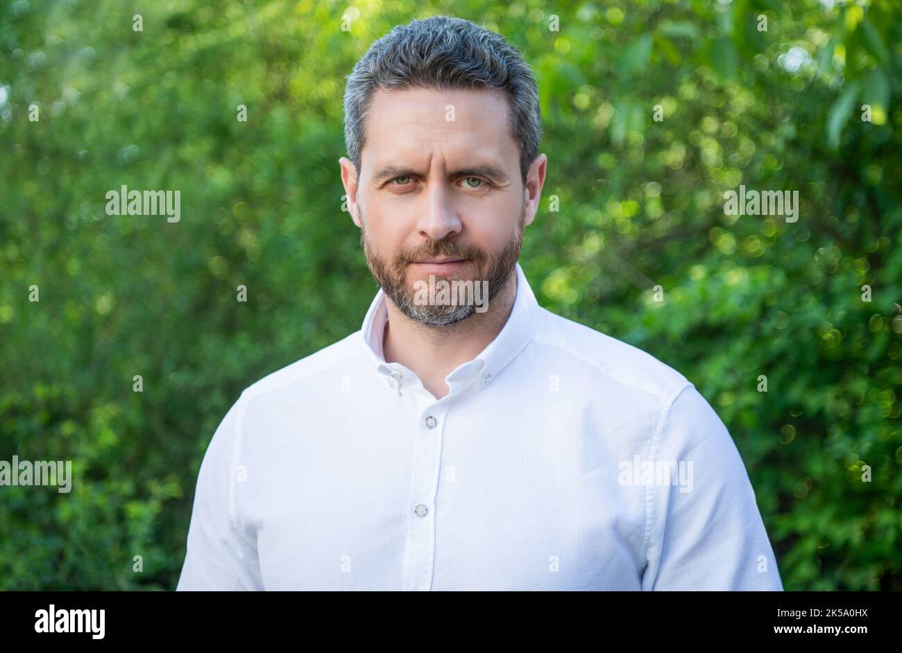 Portrait of handsome man with unshaven face in white shirt natural ...