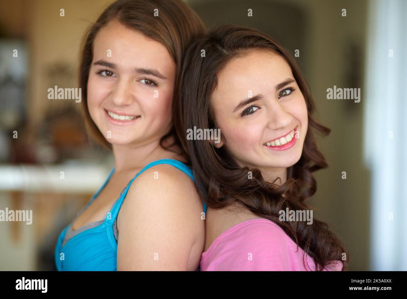 Sisters and friends. Portrait of two young sisters standing back to ...