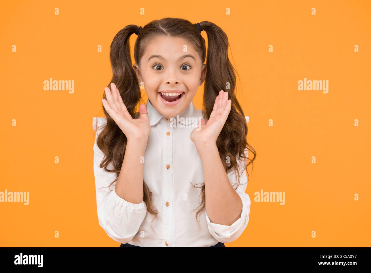 Back to school and looking delighted. surprised little girl smiling on ...