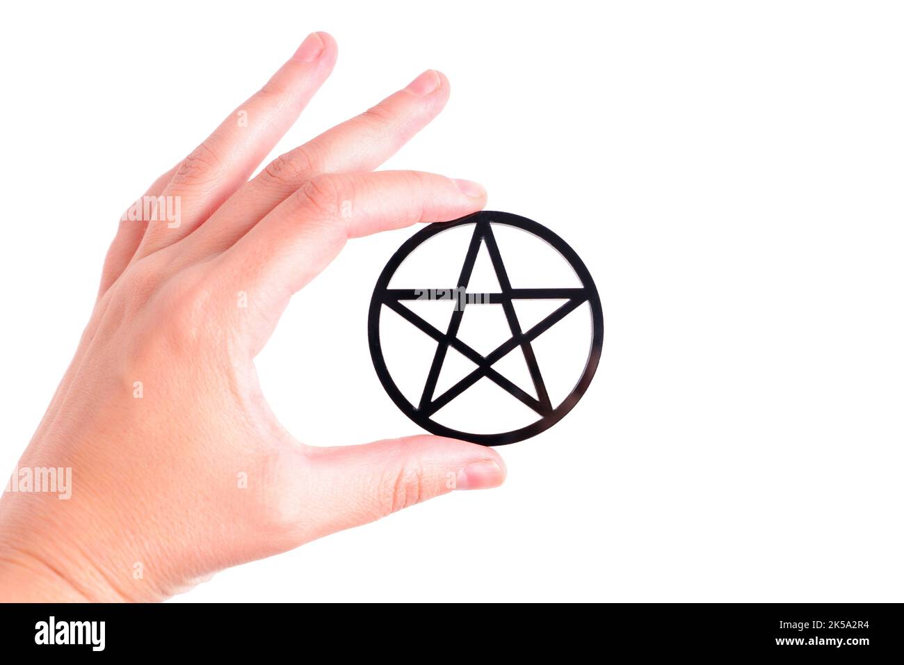 Close-up of a female hand holding a black pentagram isolated on white ...