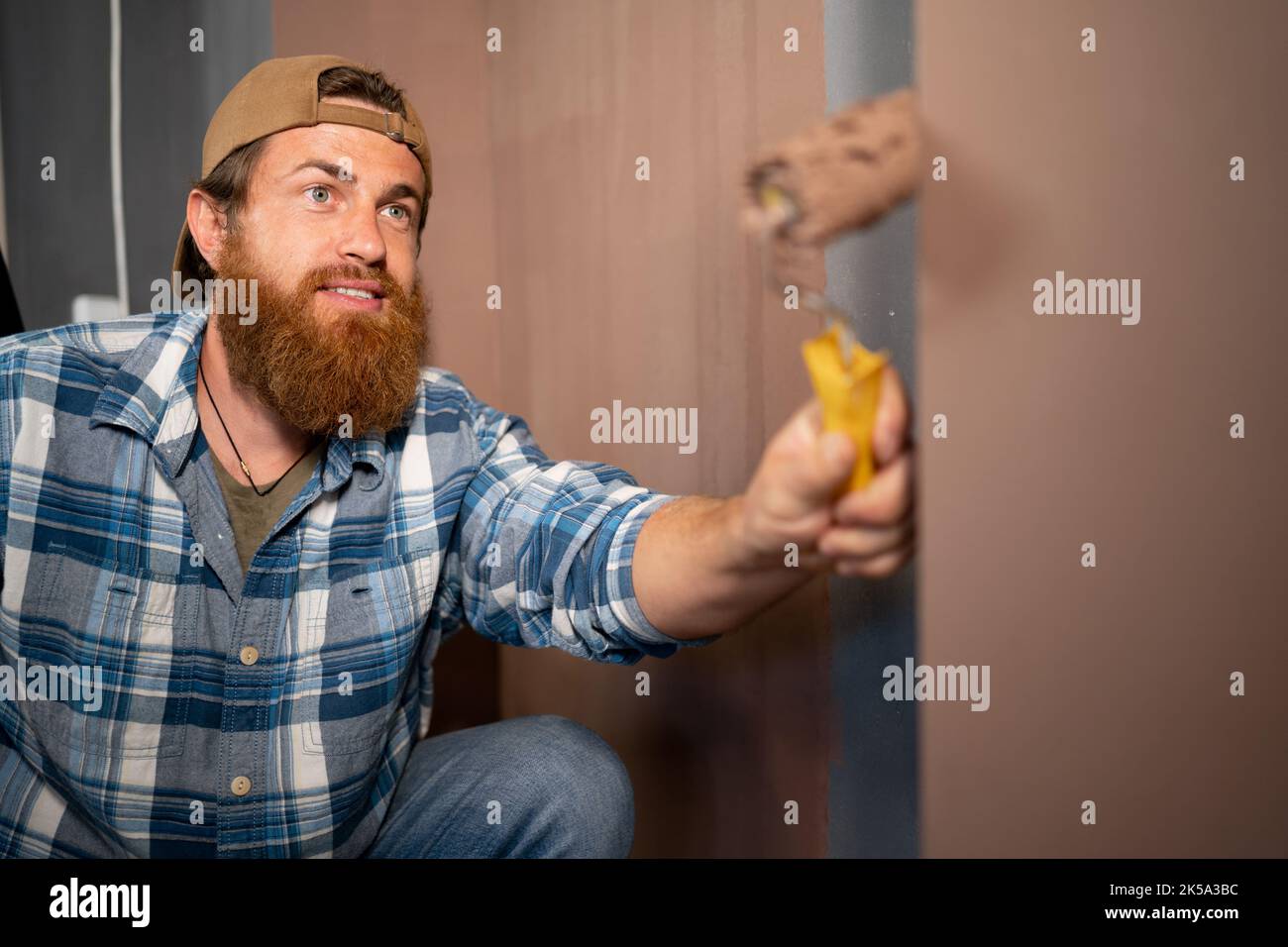 Portrait of a bearded painter painting a wall with a paint roller Stock ...