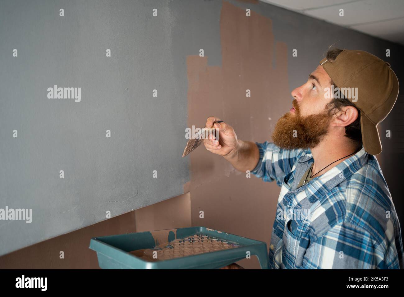 man painter painting the edges of the ceiling with paintbrush, painting ...