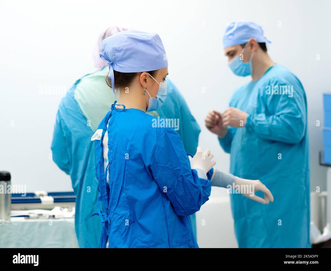A female surgeon puts sterile surgical gloves on her hands in the ...
