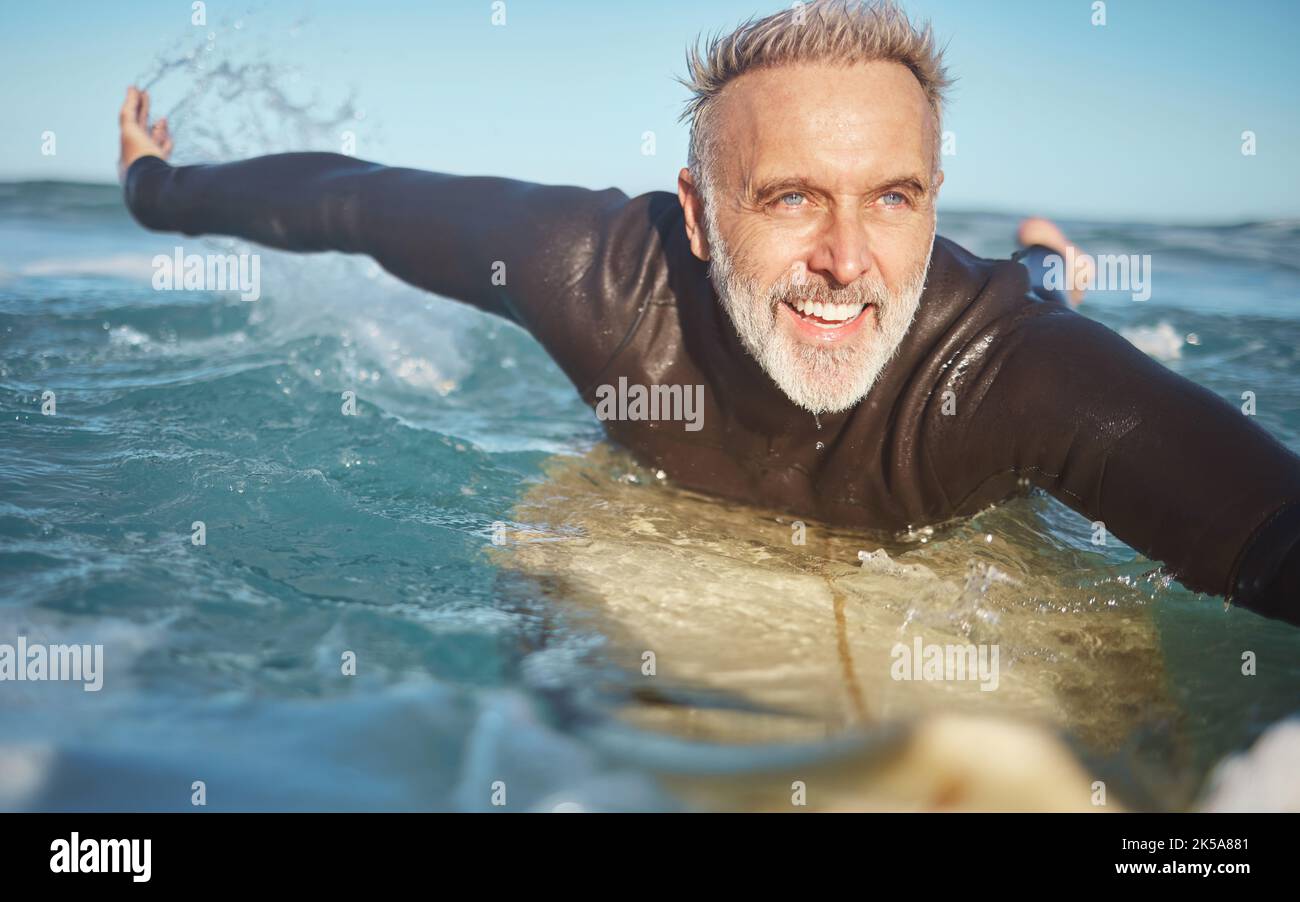 Beach, water and old man surfer swimming on a summer holiday vacation ...