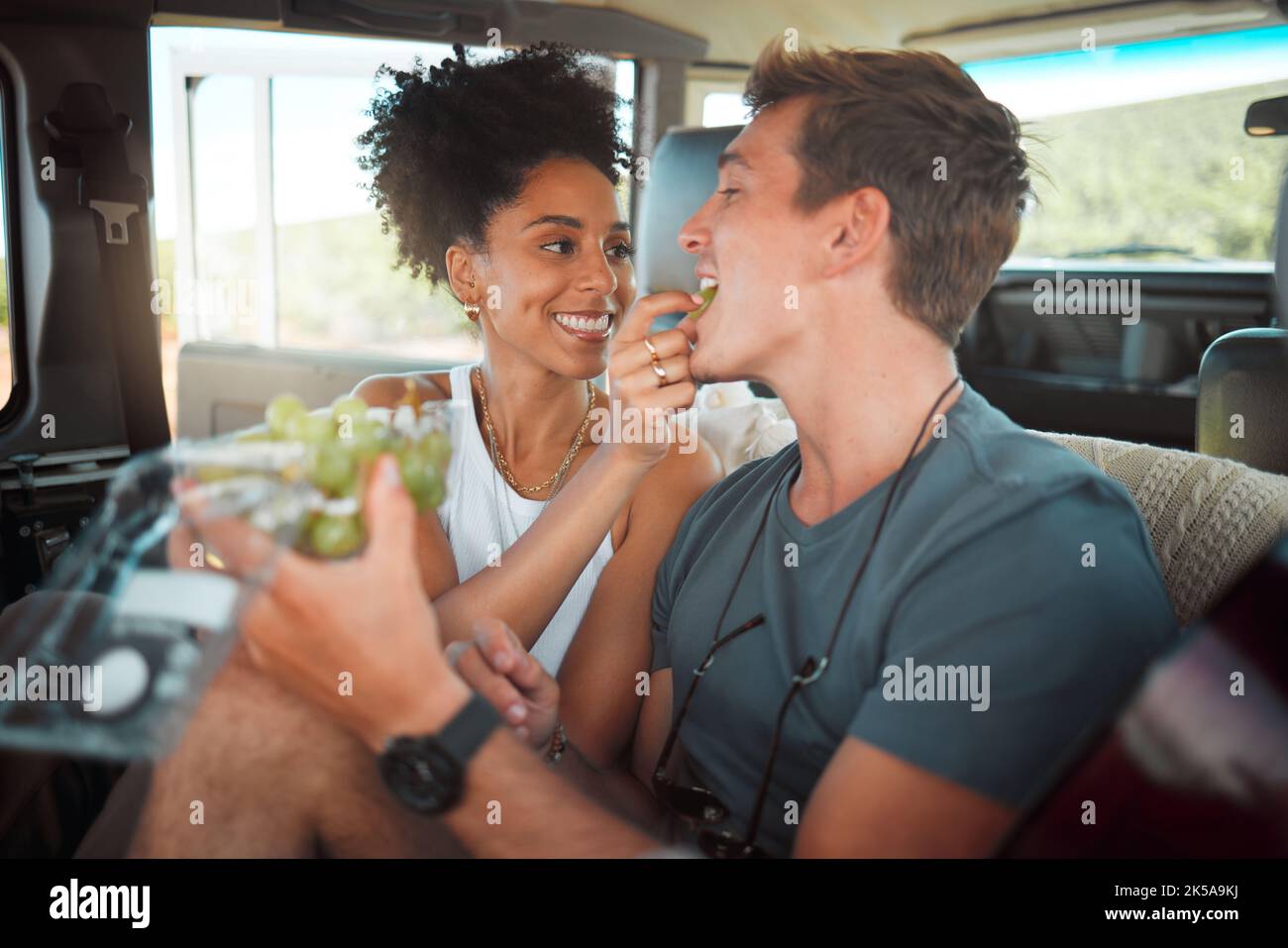 Road trip, grapes and couple eating in van on travel journey, holiday ...