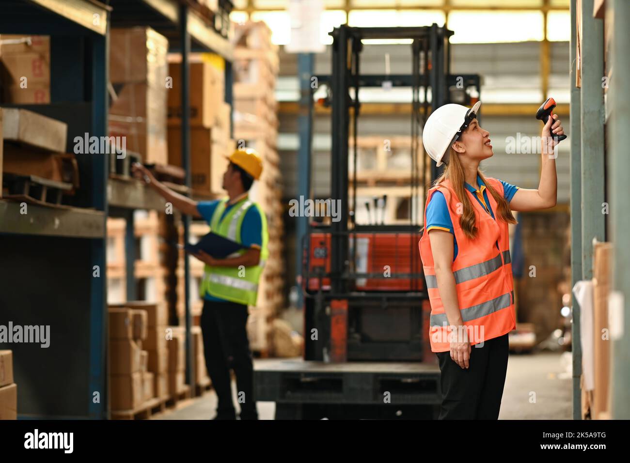 Young female warehouse worker using barcode scanner checking stock on ...