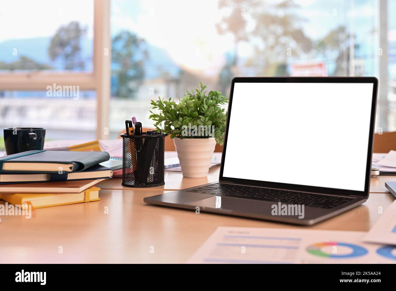 Wooden office desk with laptop computer, coffee cup, potted plant and ...