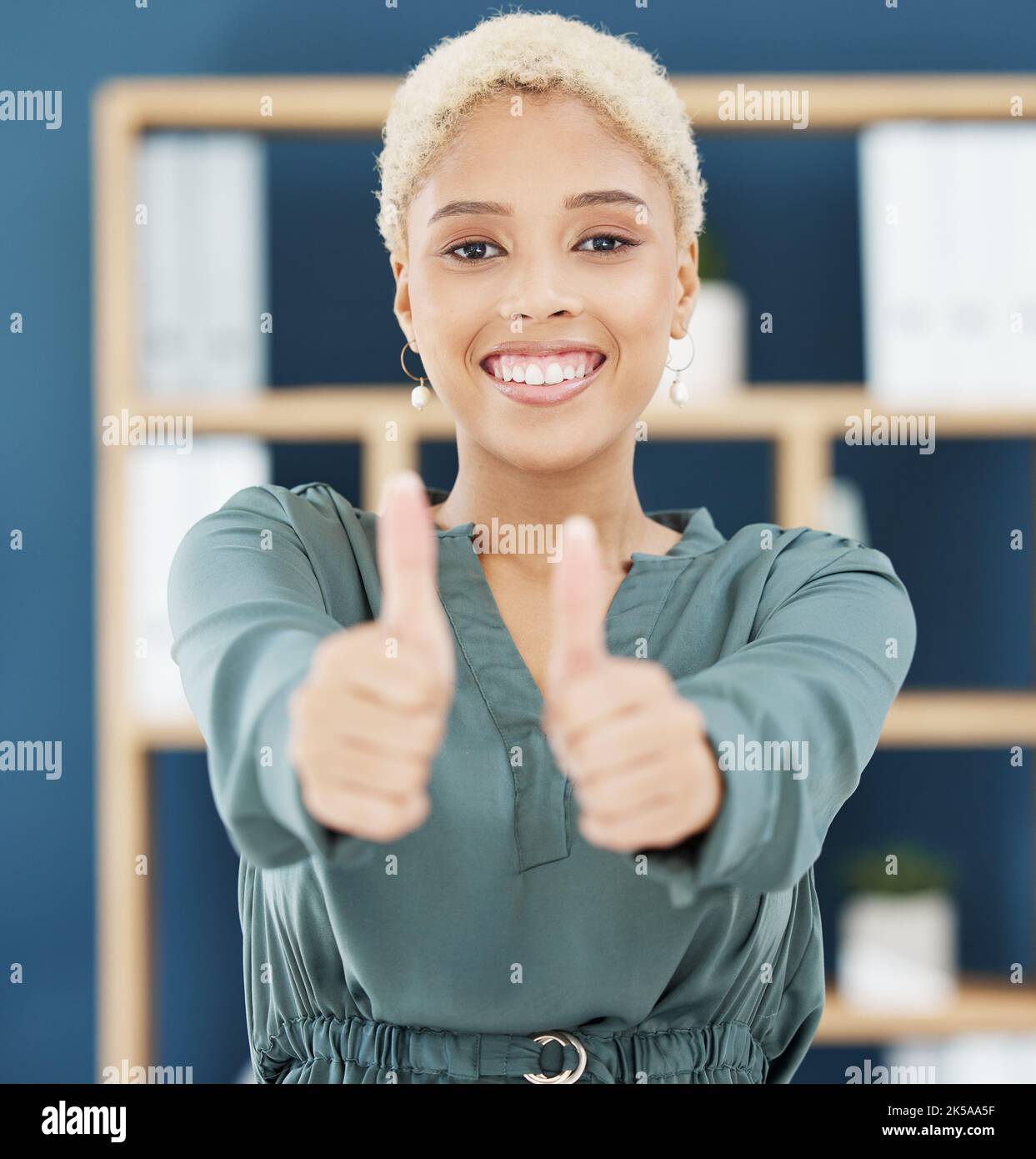 Thumbs up, success and work support hand sign worker in a office of a happy business woman ...
