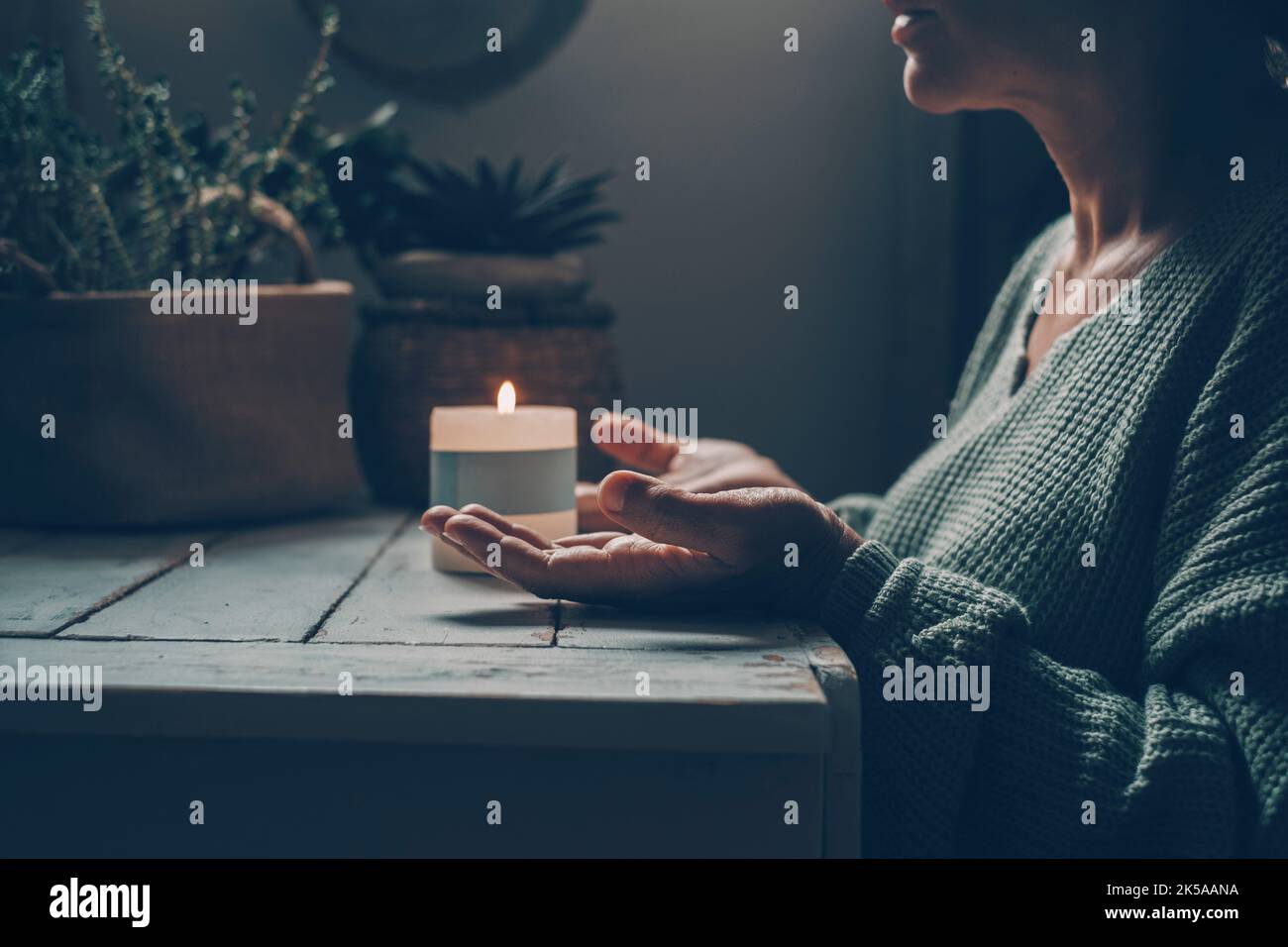 Woman at home in zen meditation activity and candlelight in background ...