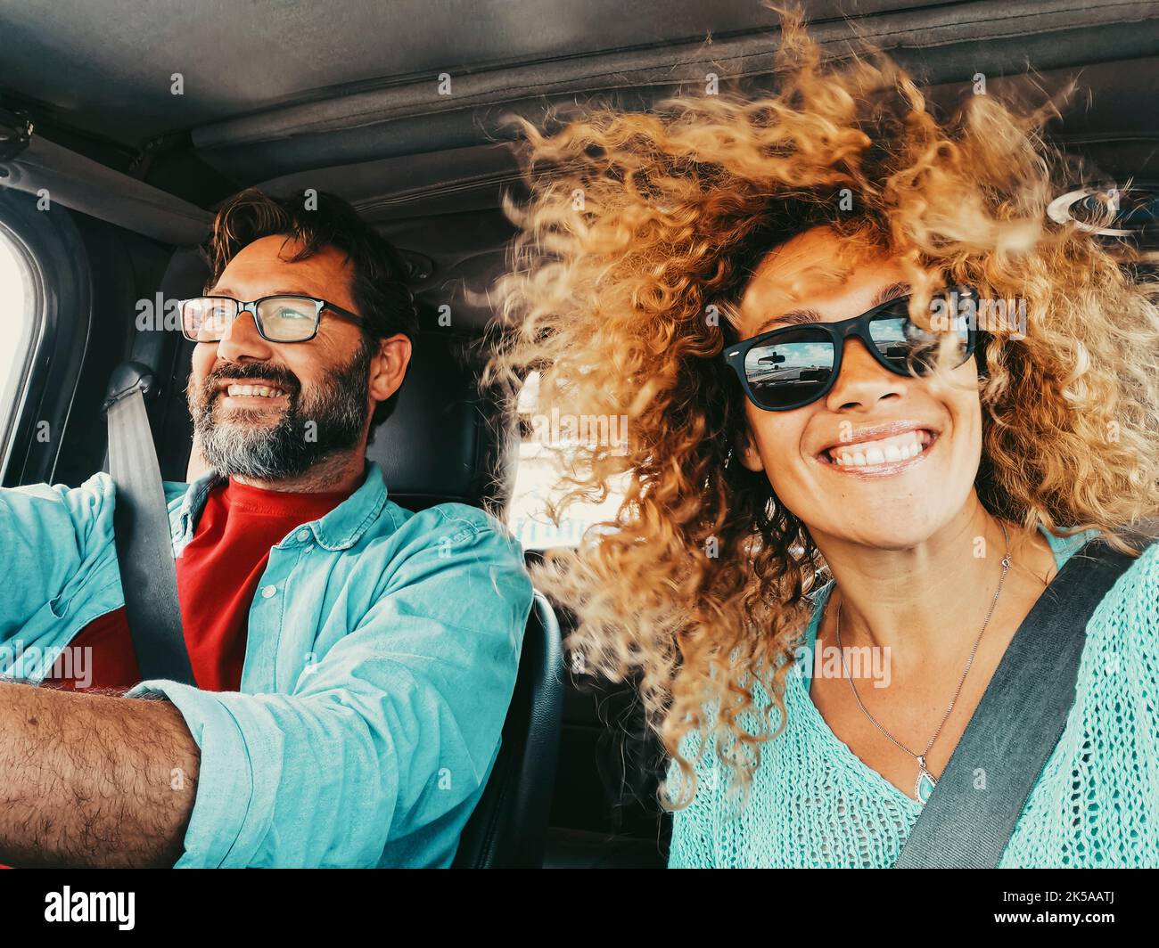 Happy young couple traveling by car together having fun. Woman taking ...