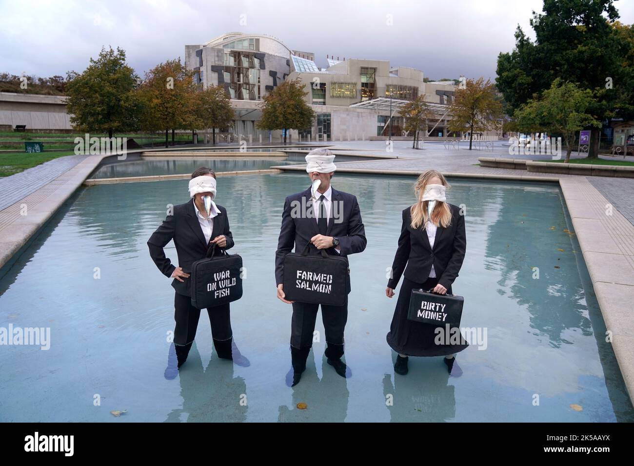 Suited performers from Ocean Rebellion, wearing blindfolds and gagged ...
