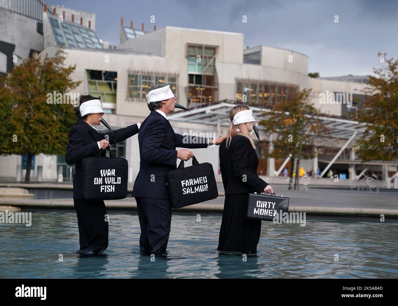 Suited performers from Ocean Rebellion, wearing blindfolds and gagged ...