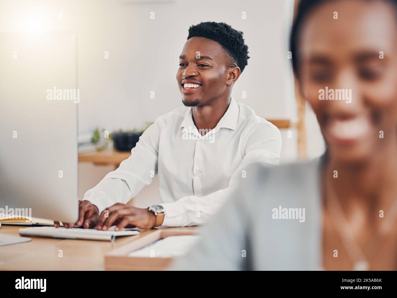 Happy employee, working on computer at desk online and writing business ...