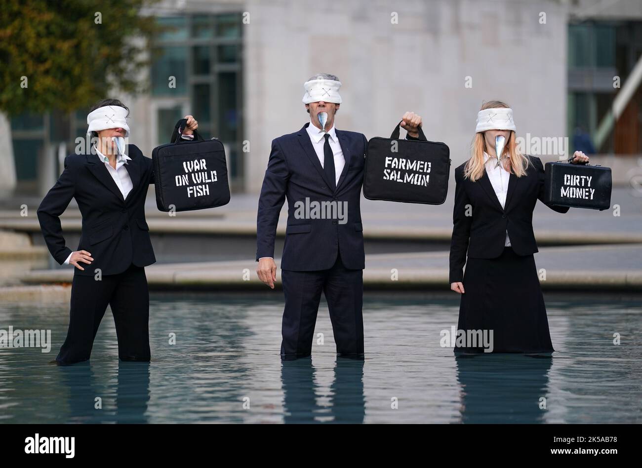 Suited performers from Ocean Rebellion, wearing blindfolds and gagged ...