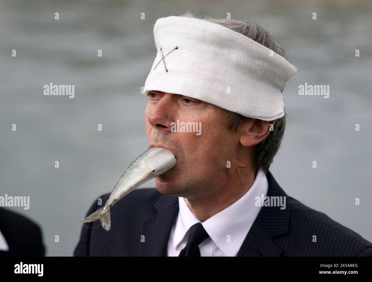 Suited performers from Ocean Rebellion, wearing blindfolds and gagged ...