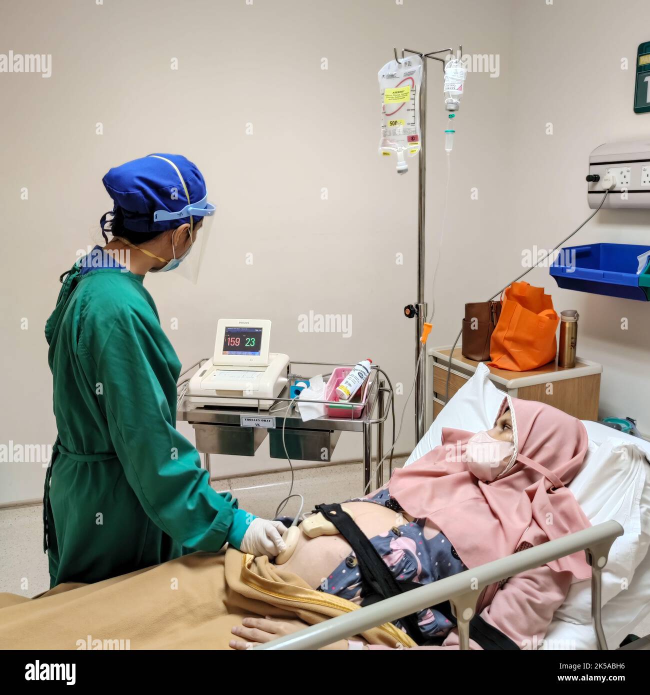 Patient laying on bed receiving medical treatment from nurse with green ...