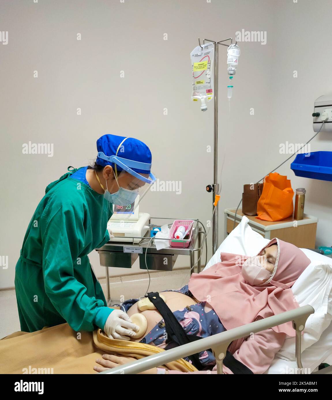 Patient laying on bed receiving medical treatment from nurse with green ...
