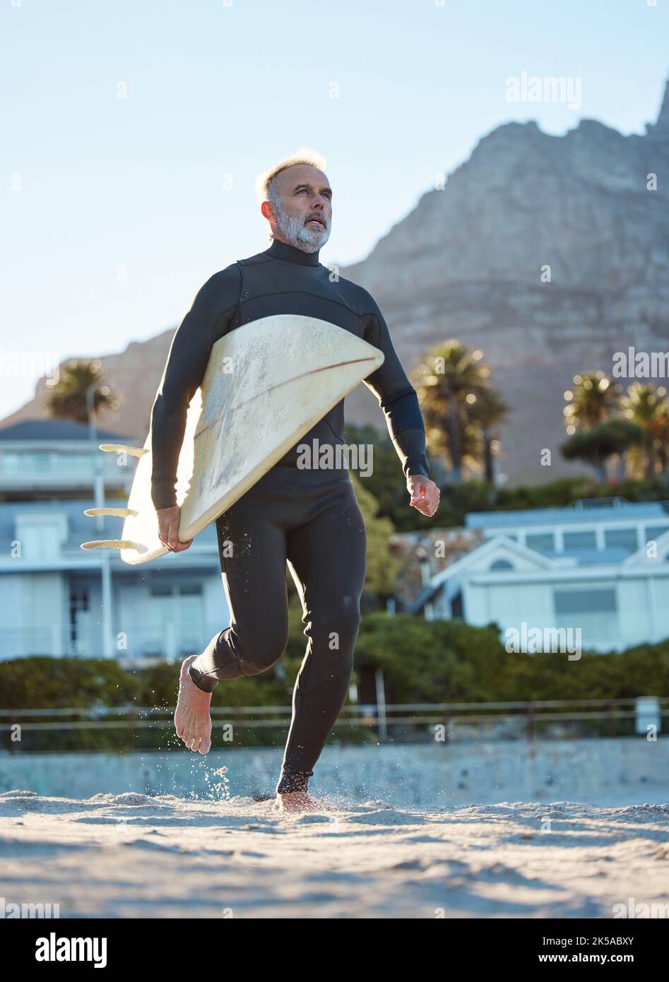 Beach, mature surfer running with surf board on sea sand and weekend water sports. Freedom ...