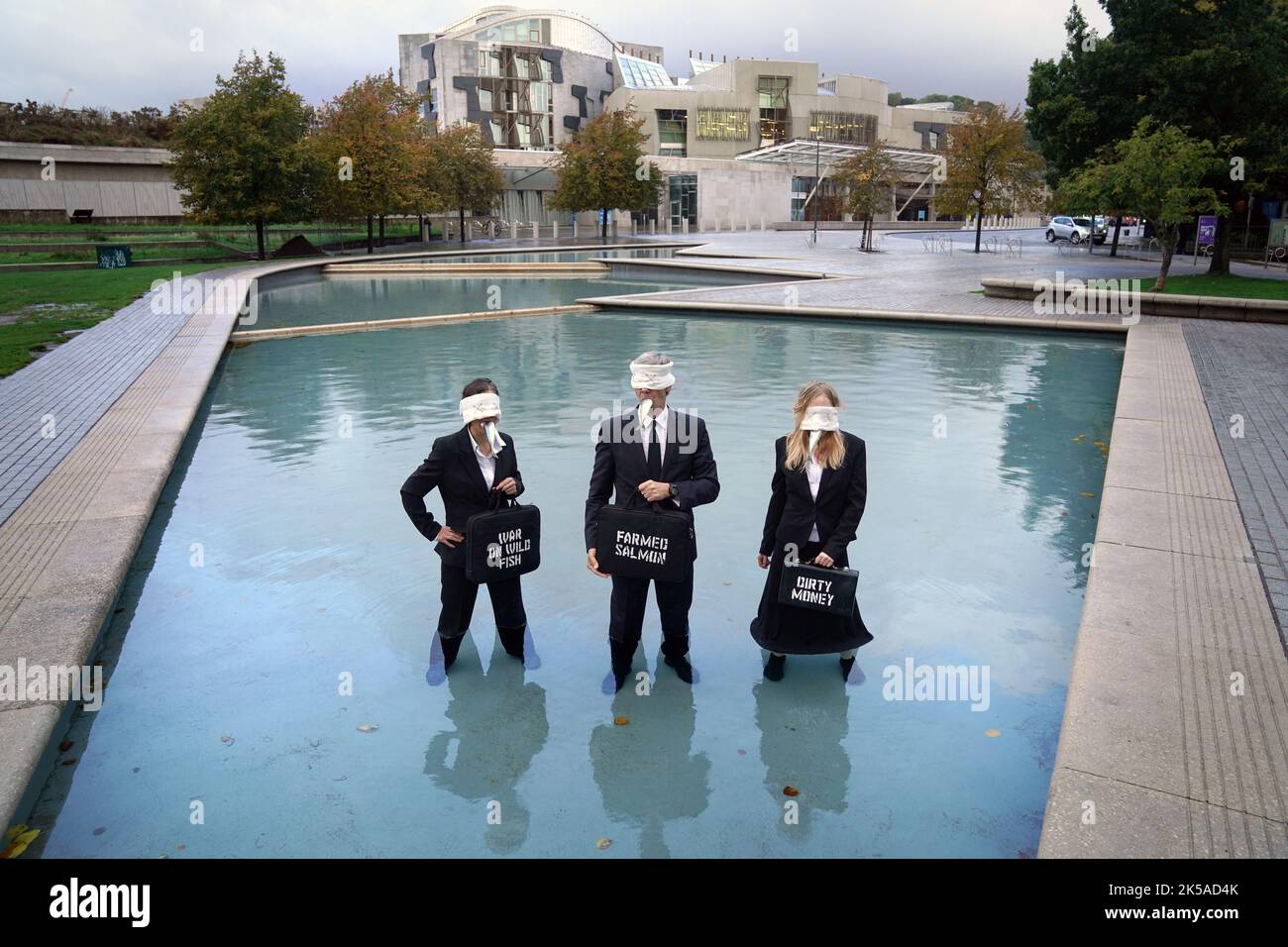Suited performers from Ocean Rebellion, wearing blindfolds and gagged ...
