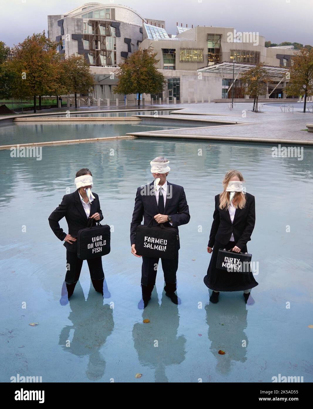 Suited performers from Ocean Rebellion, wearing blindfolds and gagged ...