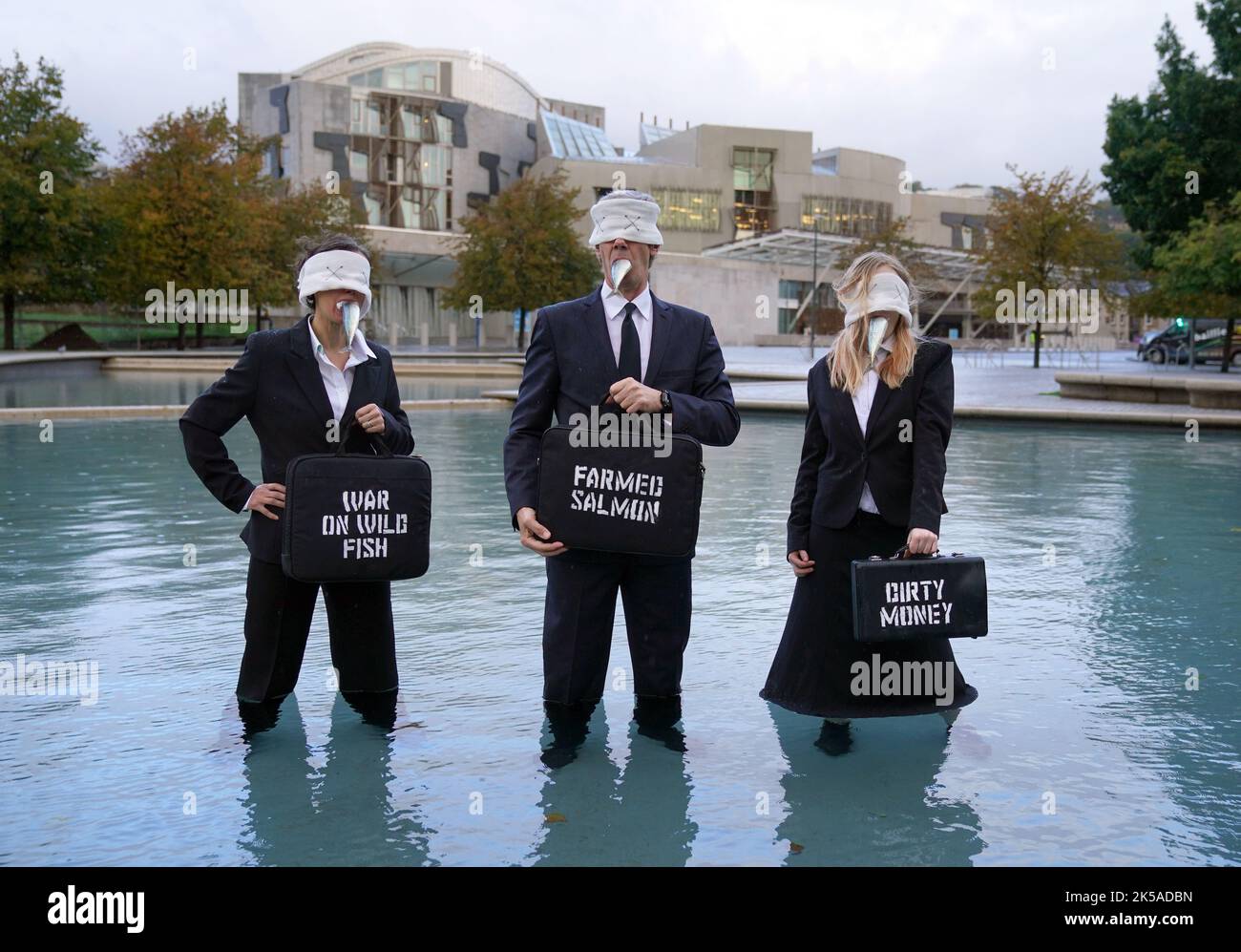 Suited performers from Ocean Rebellion, wearing blindfolds and gagged ...