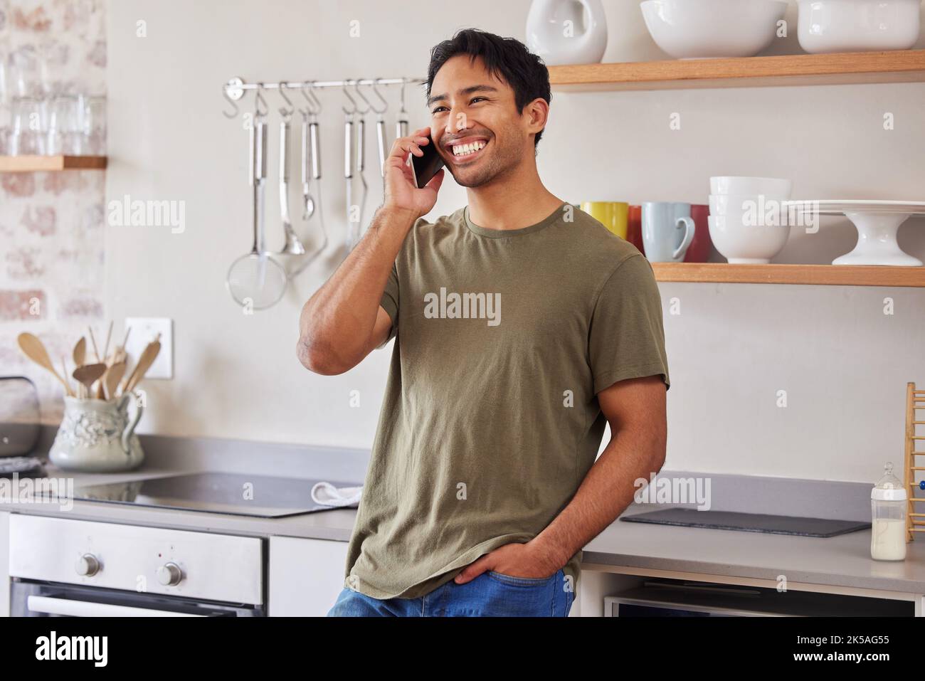 Asian man, communication and phone call in kitchen while laughing ...