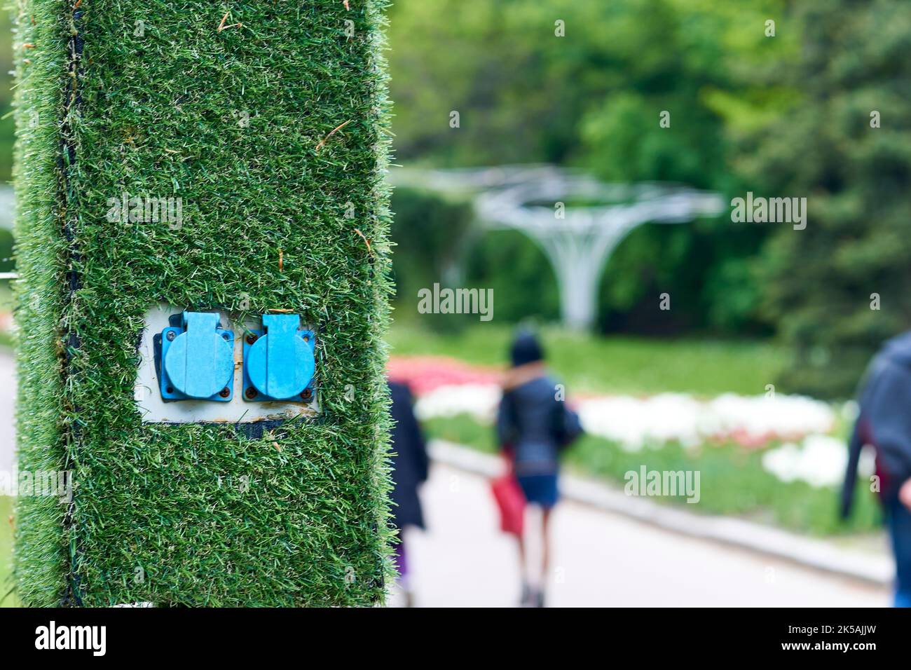 Electric sockets for charging on a pole with artificial green grass in ...