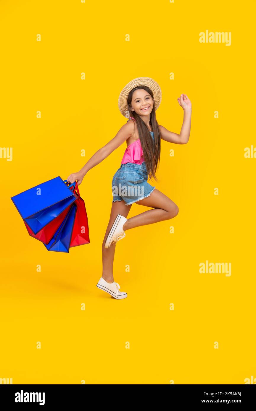 happy teen girl hurry up with shopping bags on yellow background. full ...