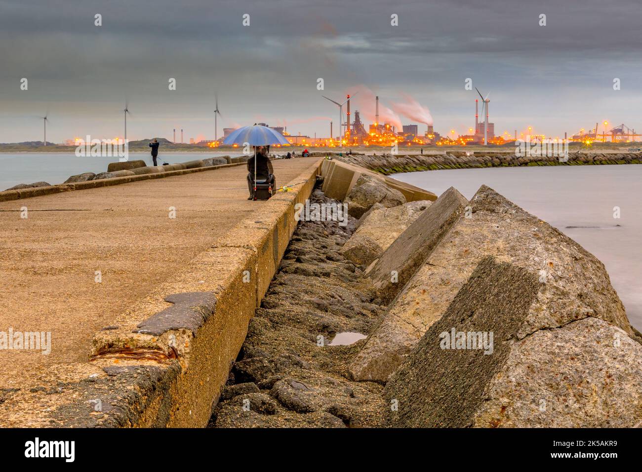 Concrete jetty near IJmuiden with angler fishermen on a cloudy ...