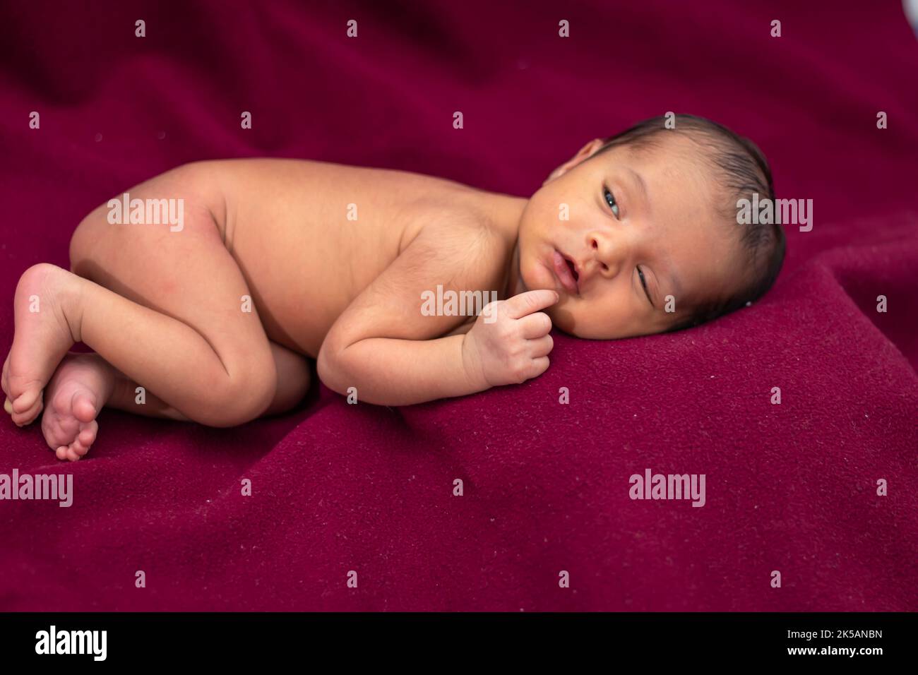 newly born baby laying on red velvet cloth with cute facial expression ...