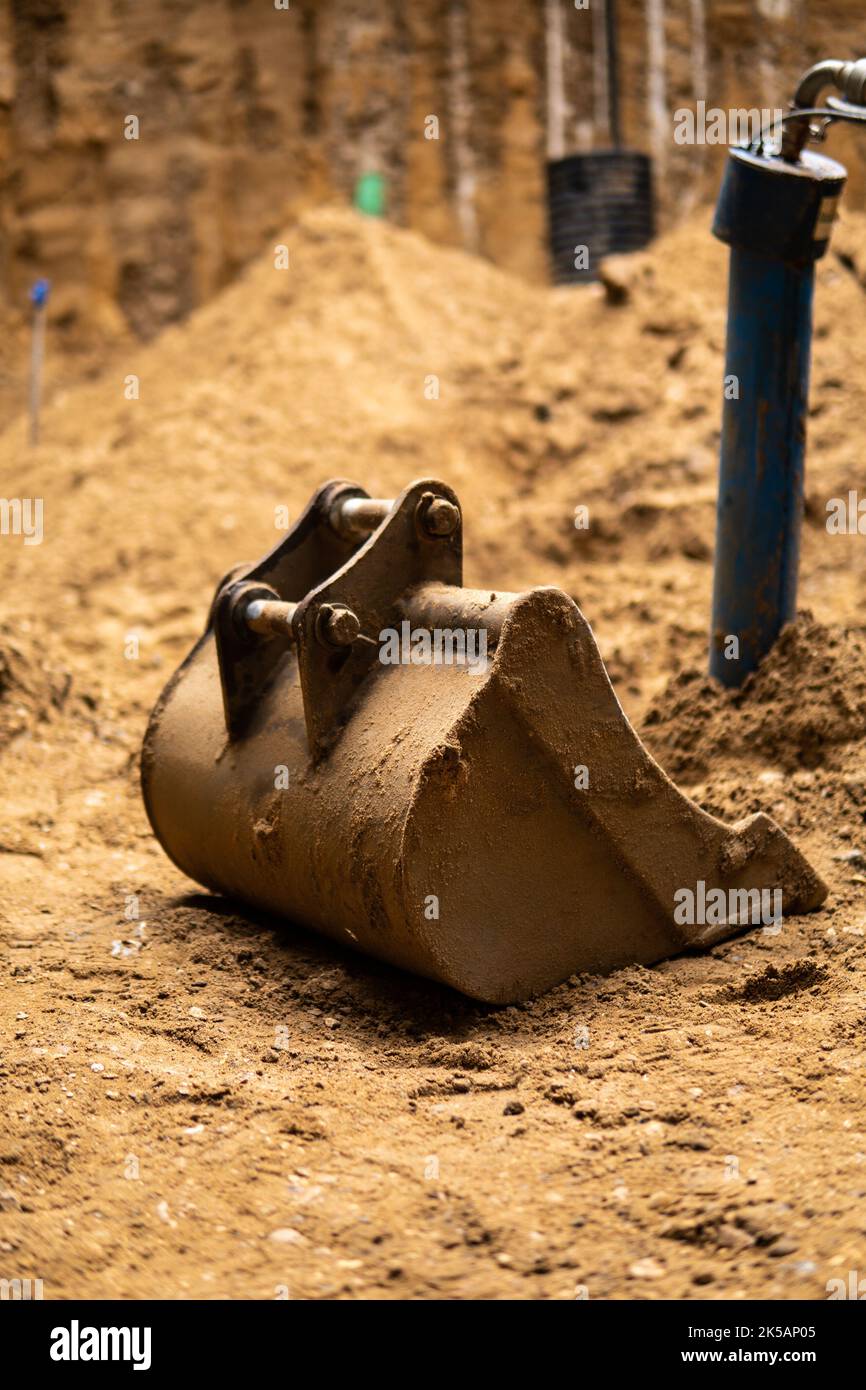 Detail of digging bucket on gravel on construction site with pipe in ...