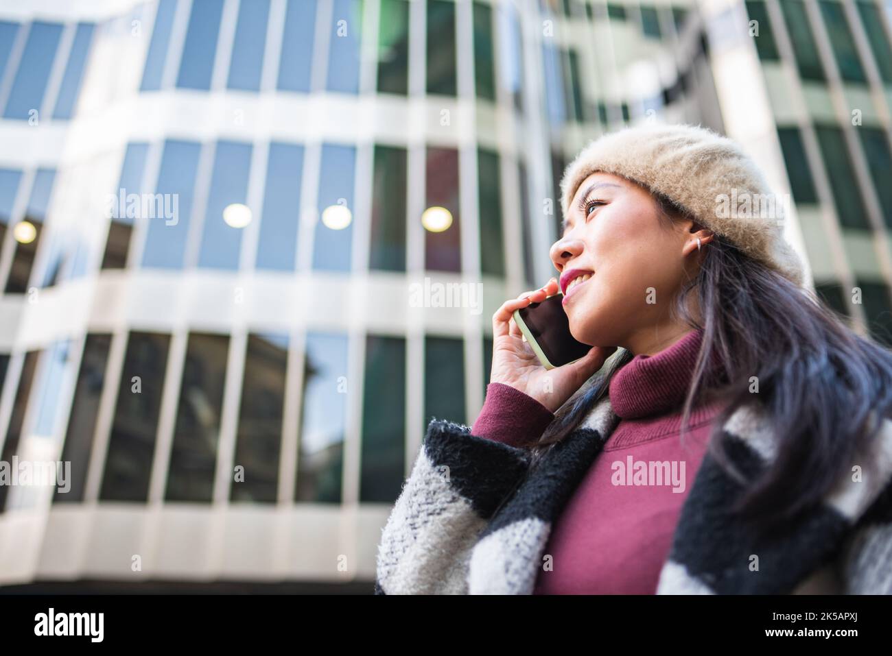 Side view of content Chinese female in outerwear and beret having phone ...