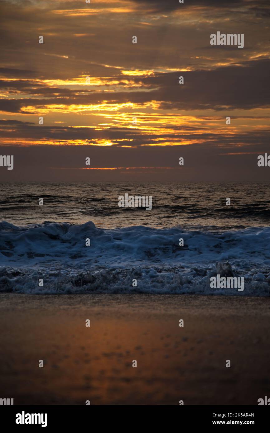 A beautiful scenery of a vast ocean with a vibrant sunset in the cloudy ...