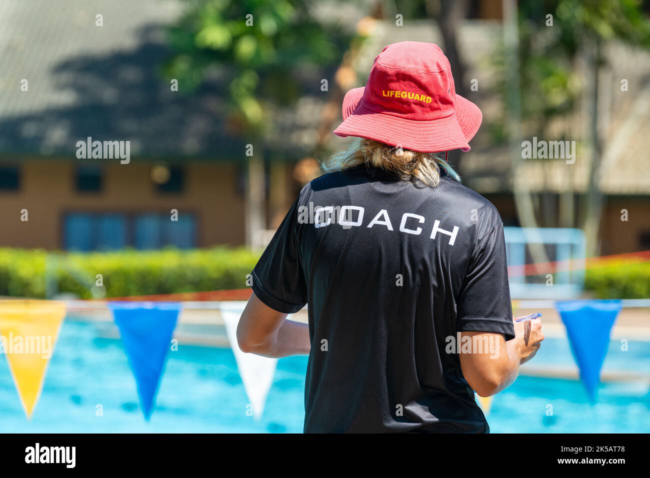 Back View Of Female Swimming Coach Wearing Coach Shirt And Red