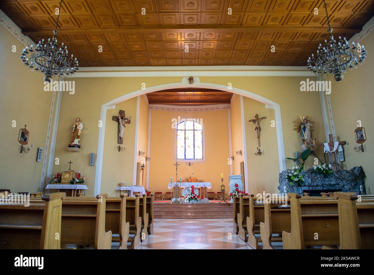 The inside of a Christian Church with wooden chairs, and statues of ...