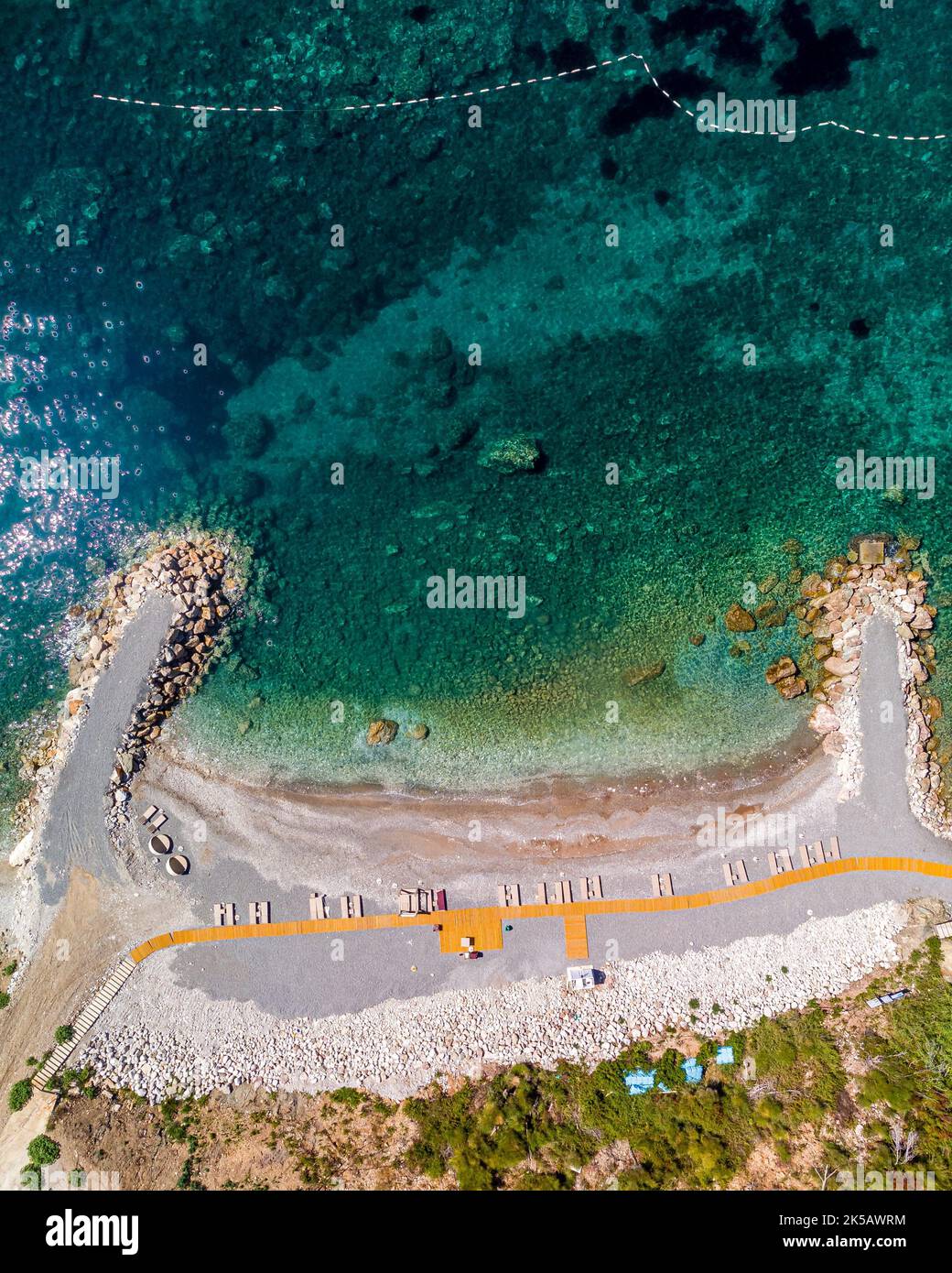 A vertical aerial shot of Drobni pijesak rocky beach with a green ...