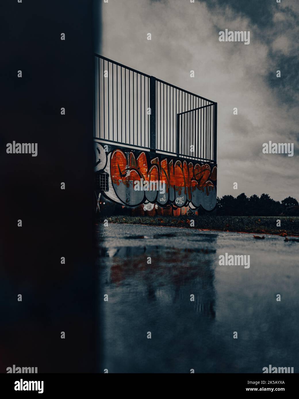 A vertical shot of colorful graffiti on a wall below a fence in a ...