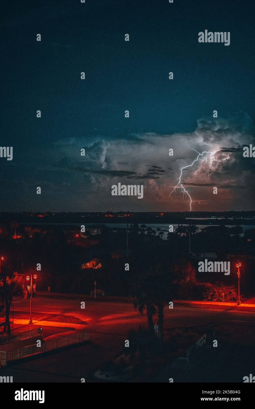A vertical shot of a lightning strike caught over a city during the ...
