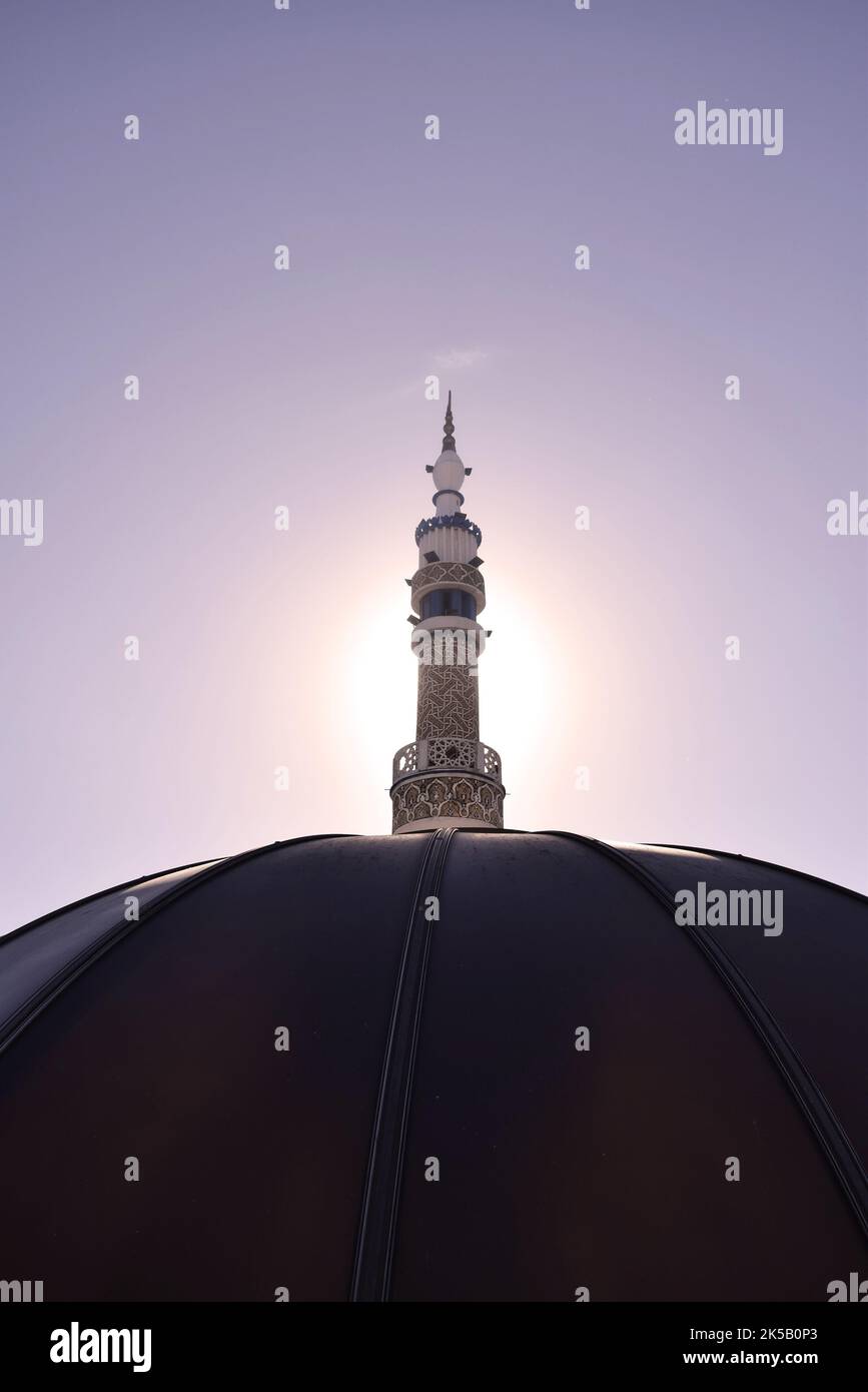 A vertical shot of a tall tower on a dome-roofed building with the sun ...