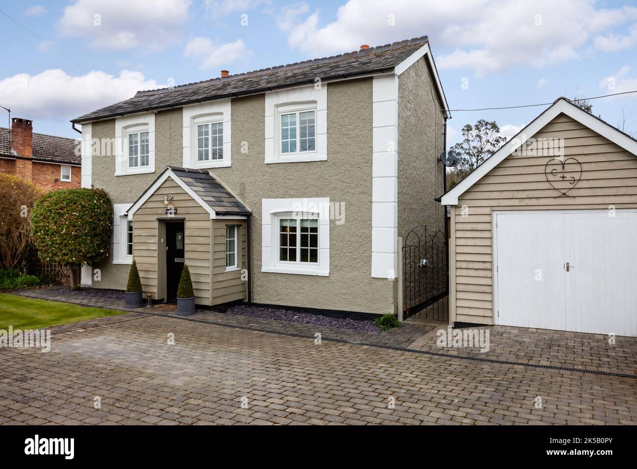 Detached traditional cottage with paved driveway and garage Stock Photo ...
