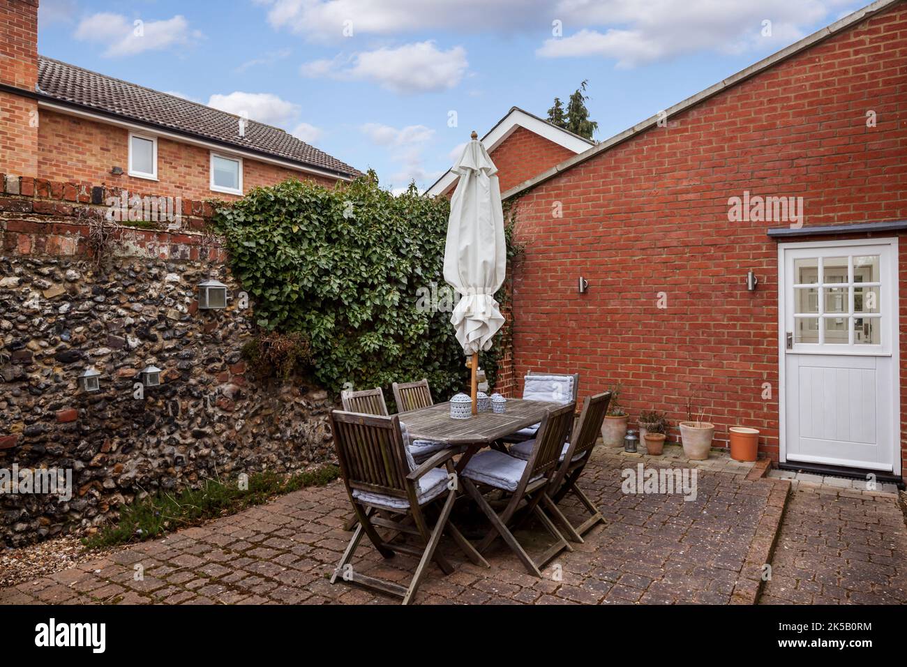 Walled courtyard garden with table and chairs Stock Photo - Alamy