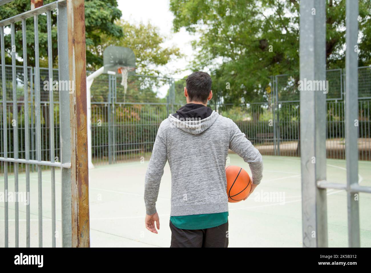 Rear view of a basketball player entering to a public outdoor court ...